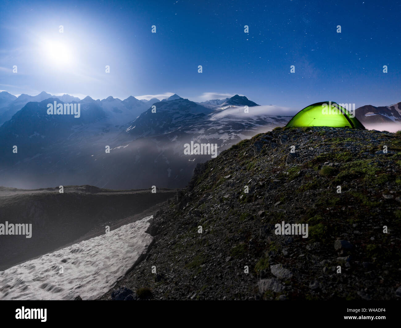 Moonlit scene with illuminated green tent under starry night - fog ...