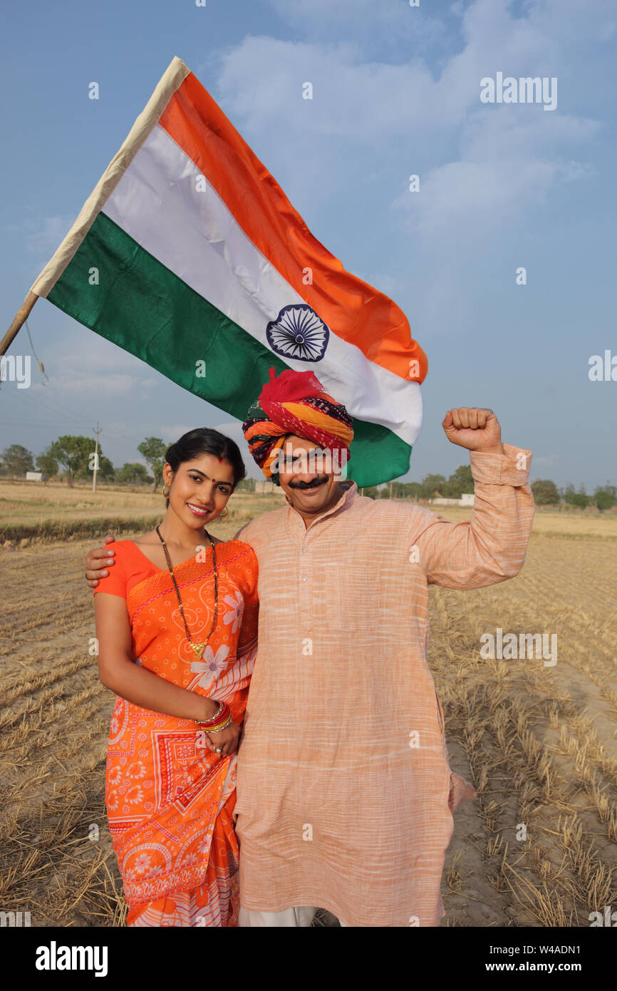 Portrait of a rural couple smiling with Indian flag in the background ...