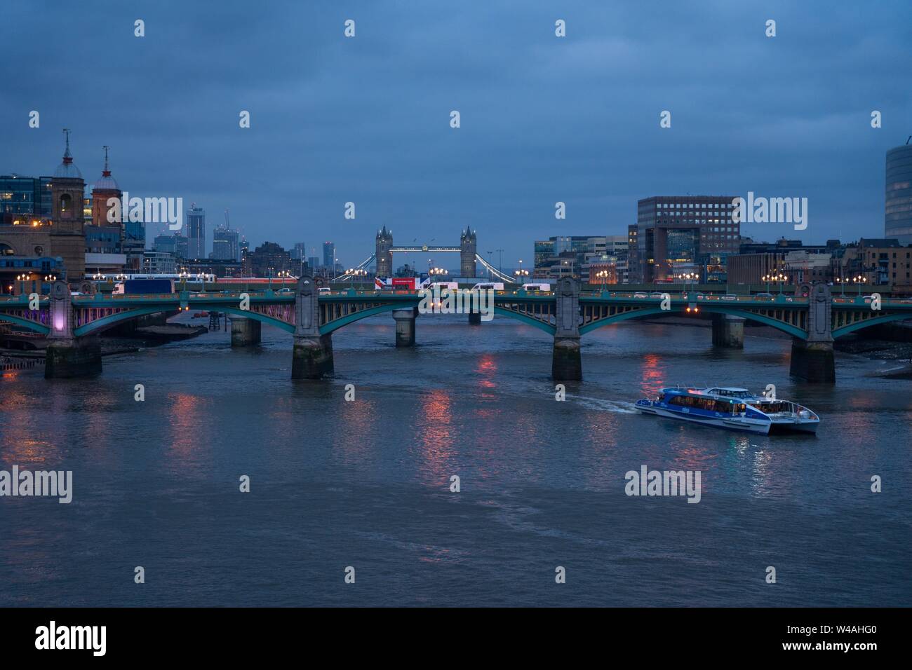 Wide shot of a city bridge over water with a boat passing under it ...
