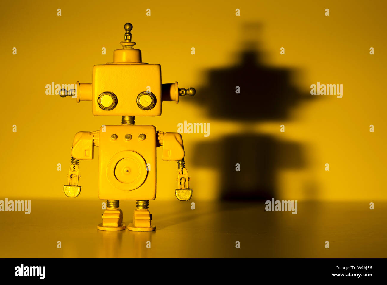 Cute, yellow, handmade robot on a yellow background with hard shadow ...