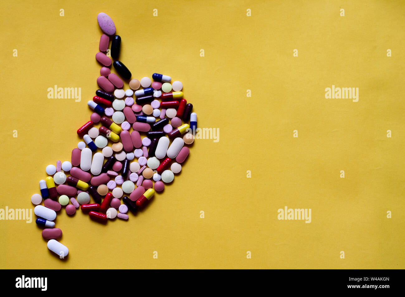 Medicine pills tablets capsules in shape of human stomach in yellow ...