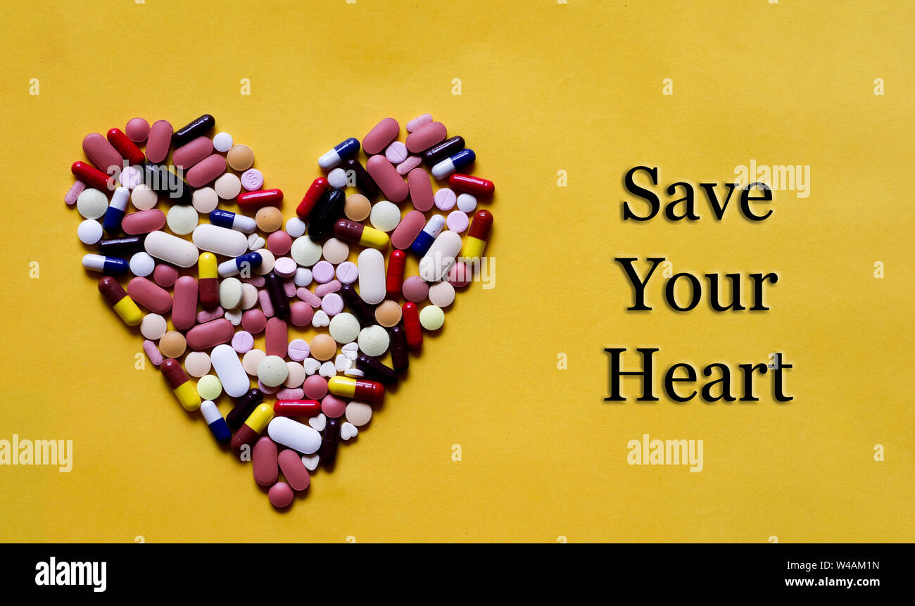 Medicine pills tablets capsules in shape of human heart in yellow ...