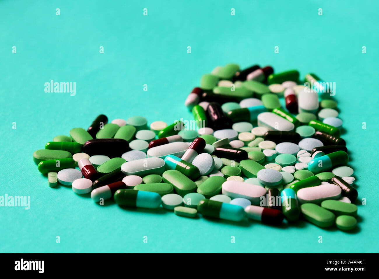 Medicine pills tablets capsules in shape of human heart in blue ...