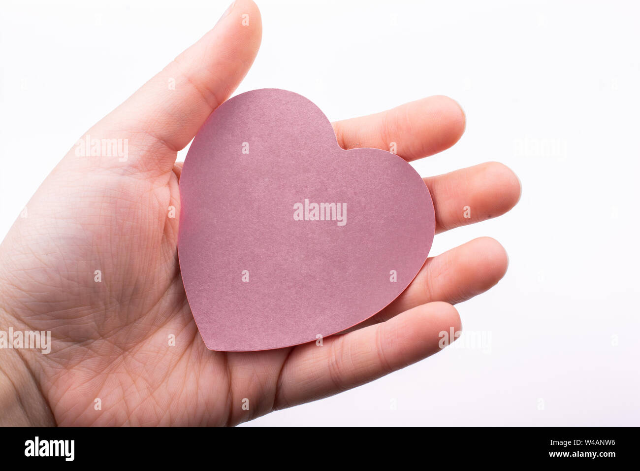 Pink color heart shaped paper in hand as love concept Stock Photo - Alamy