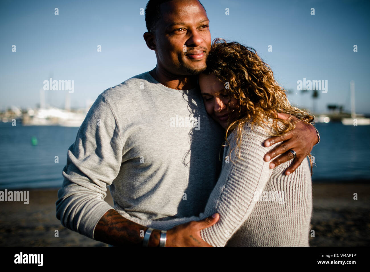 Multi racial couple embrace on beach at sunset Stock Photo - Alamy