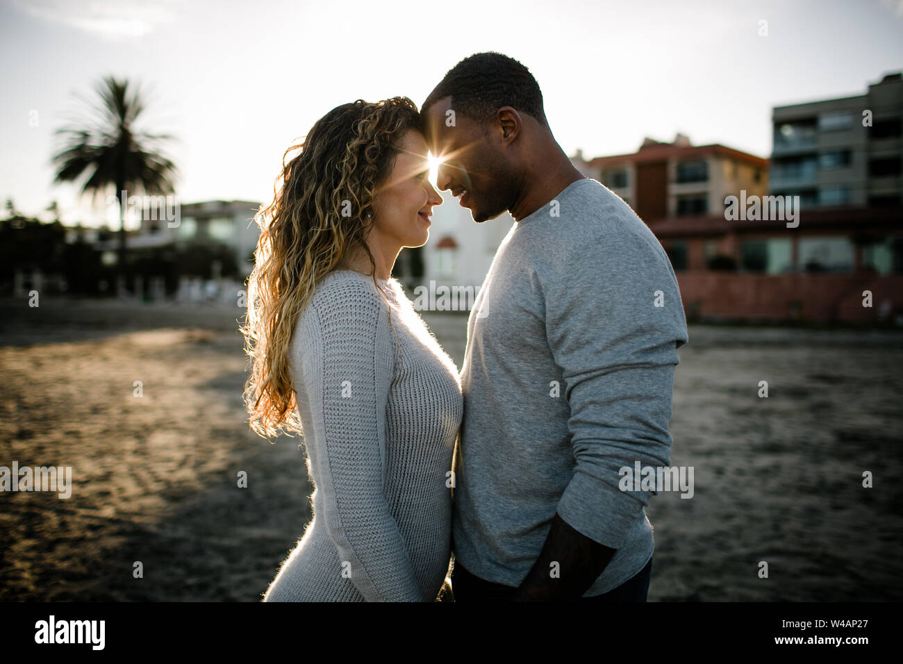 Multi racial couple embrace on beach at sunset Stock Photo - Alamy