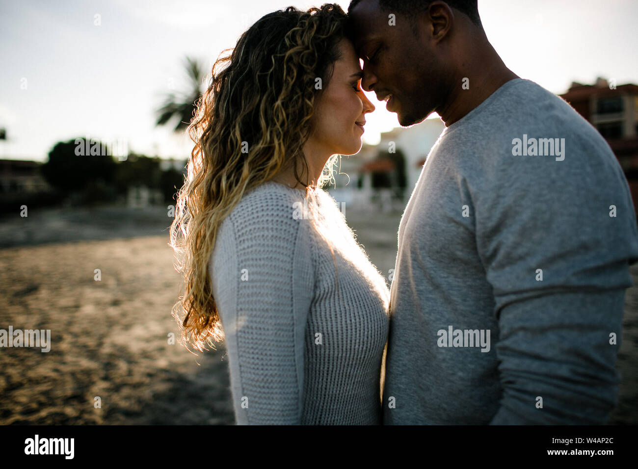 Multi racial couple embrace on beach at sunset Stock Photo - Alamy