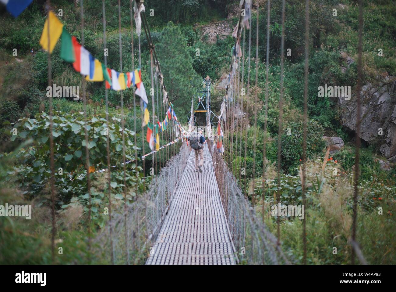 Man walking over bridge with backpack Stock Photo - Alamy