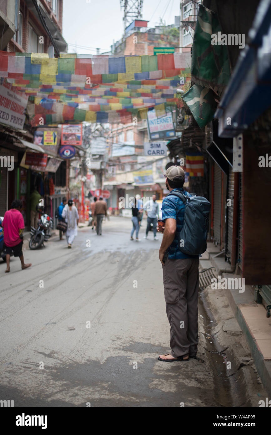 Young man with backpack standing in street of Asia with Himalayan flag ...