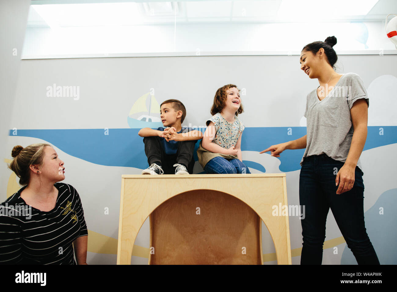 Teachers interact with two students sitting on top of a cube Stock ...