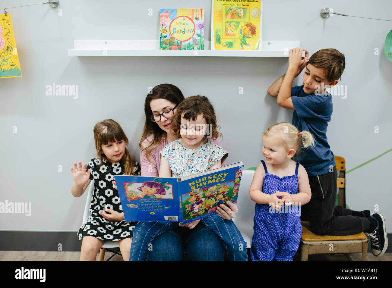 Teacher and four students read a book together Stock Photo - Alamy