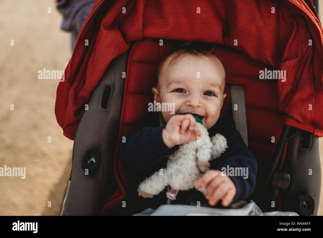 Smiling portrait of baby boy in stroller with pacifier Stock Photo - Alamy