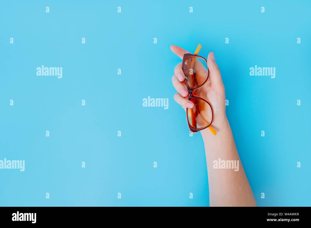 One female hand gently holds glasses, squeezing them with fingers, on a ...