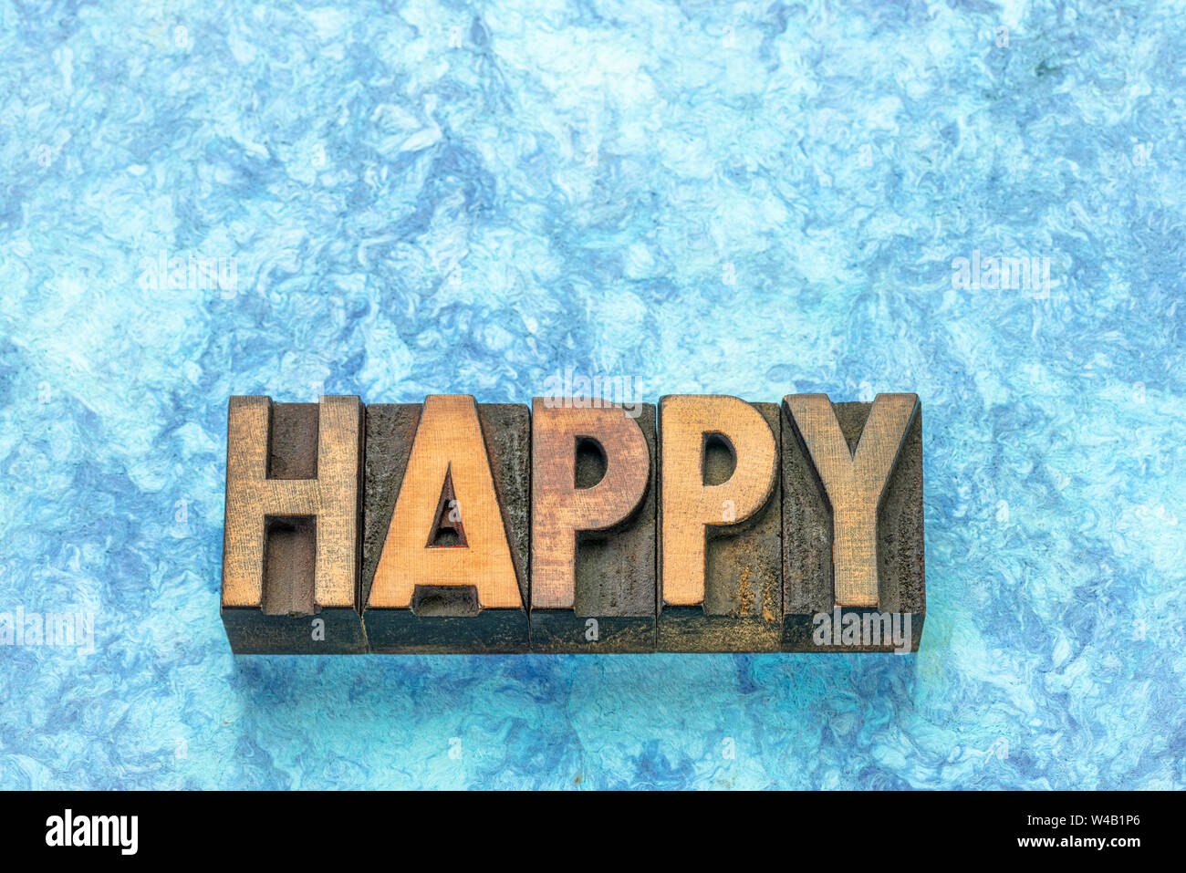 happy word in vintage letterpress wood type against blue bark paper ...