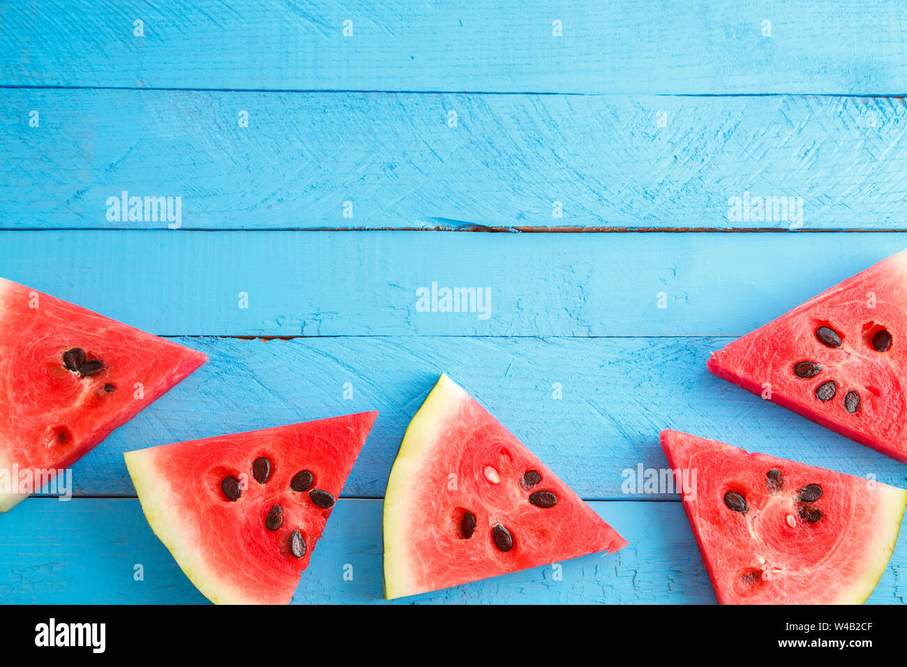 red scarlet watermelon pieces on blue wooden vintage background. summer ...