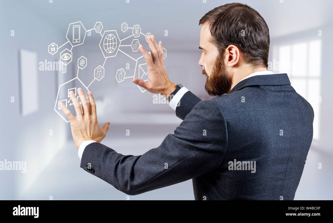 Businessman manages virtual glowing icons by hands Stock Photo - Alamy