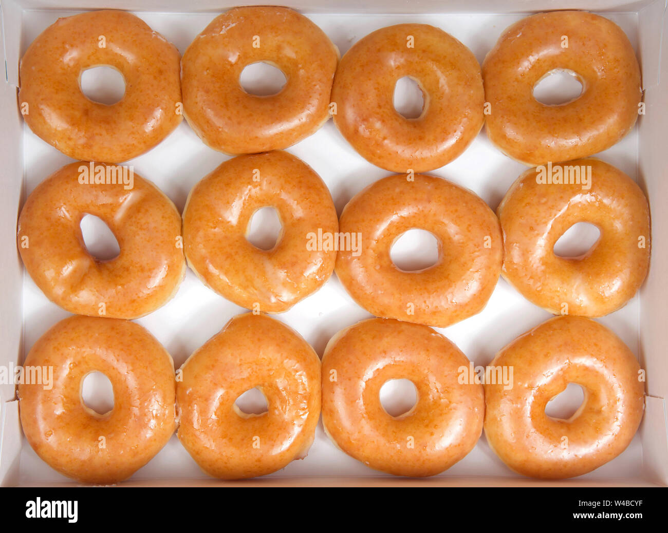 Top view flat lay of plain glazed donuts in a white box isolated. One ...