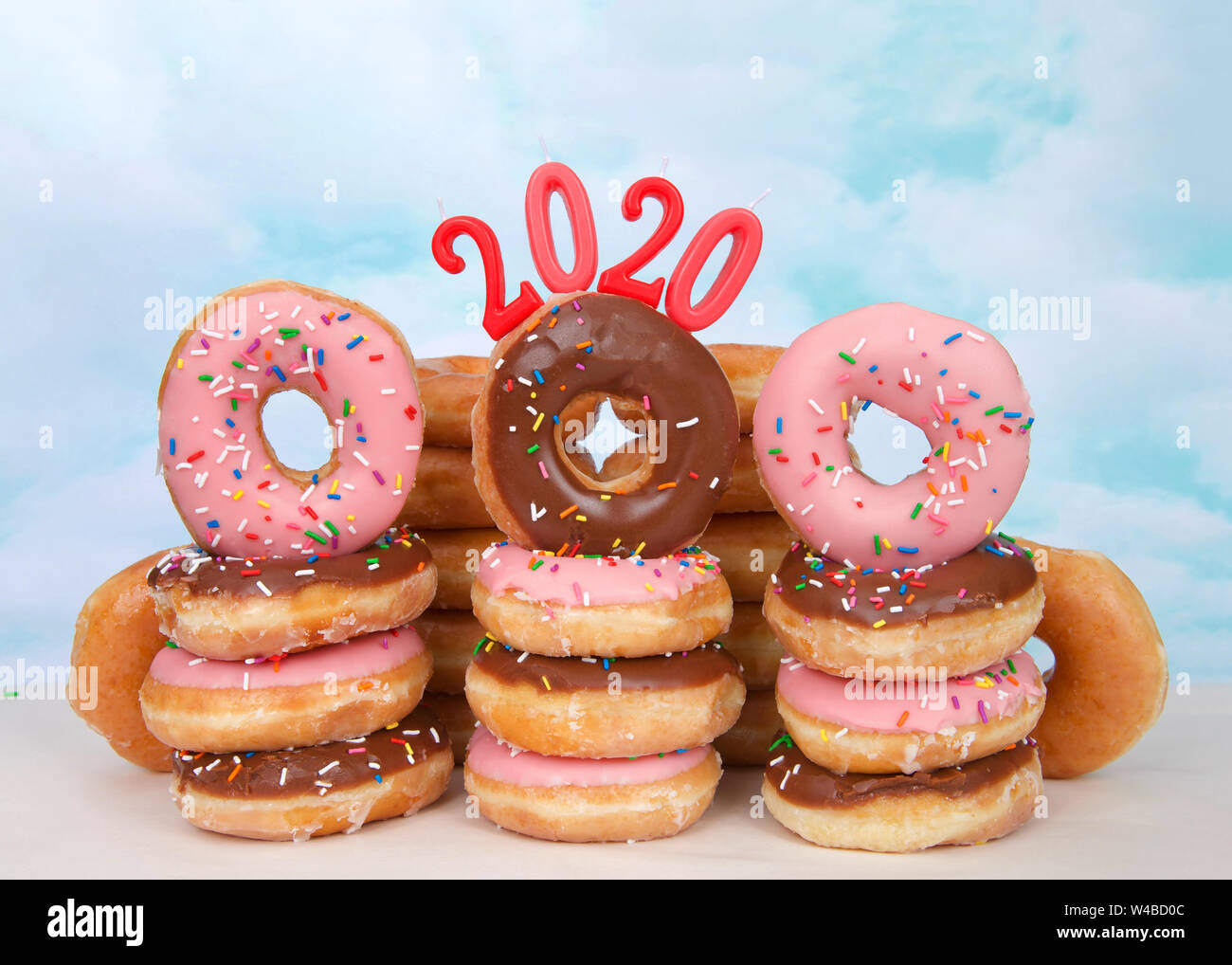 Variety of glazed donuts stacked with 2020 year candles, blue ...