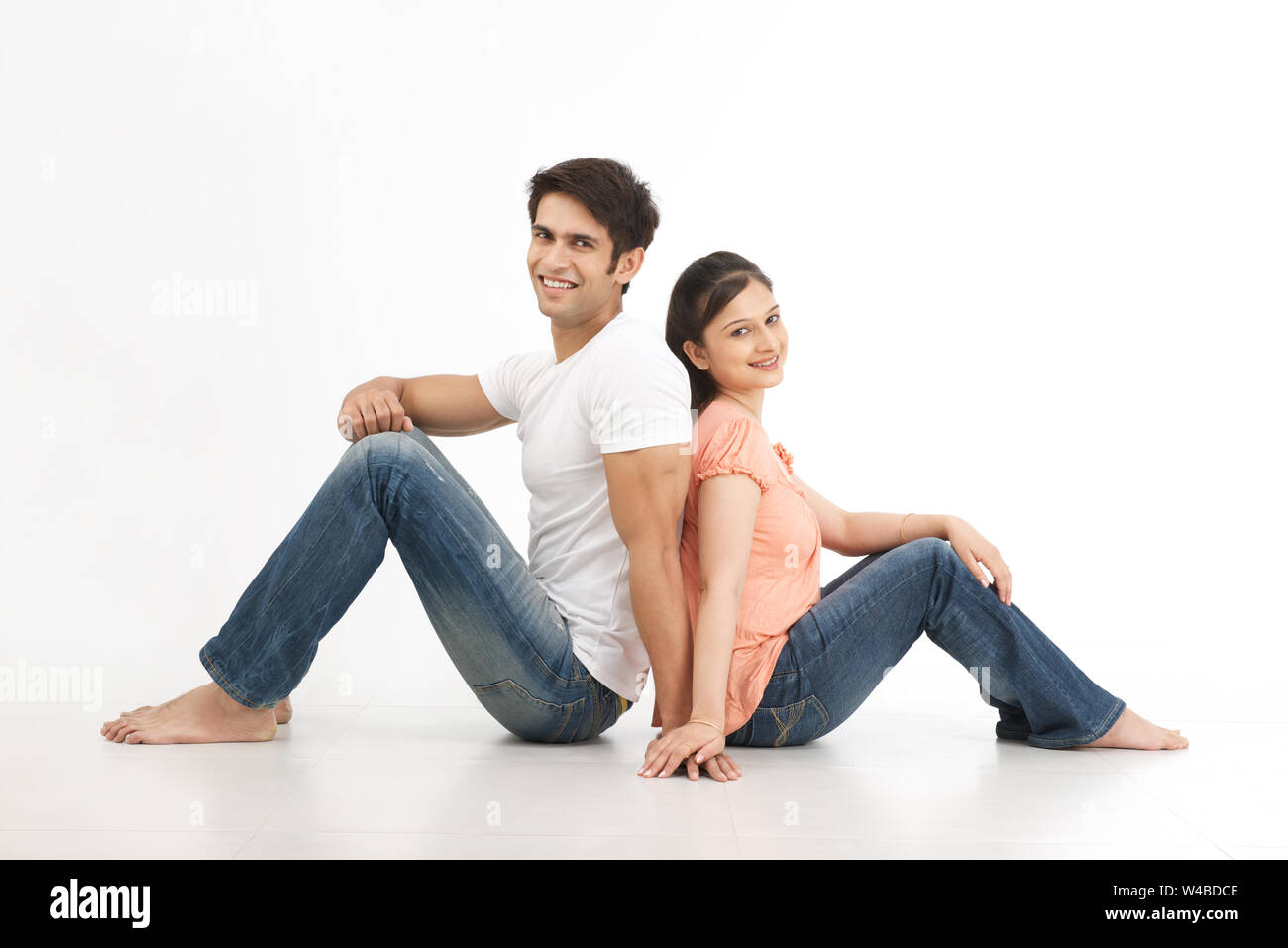 Couple sitting back to back and smiling Stock Photo - Alamy