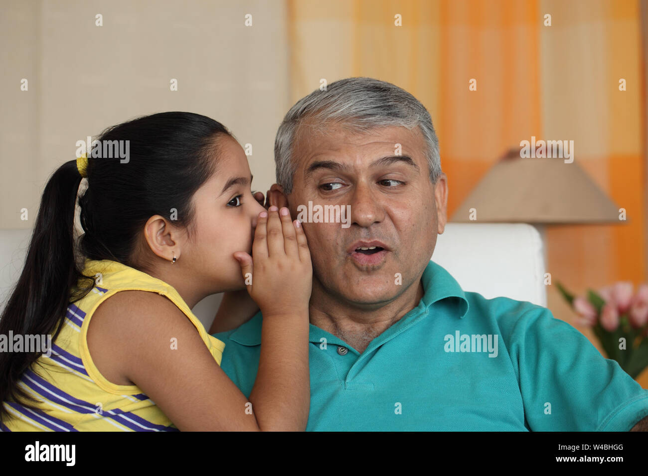 Indian girl whispering into her grandfather ear Stock Photo - Alamy