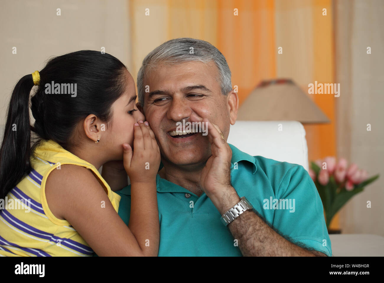 Girl whispering into her grandfather ear Stock Photo - Alamy