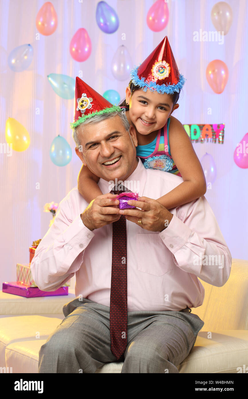 Girl giving gift to his grandfather at home Stock Photo - Alamy