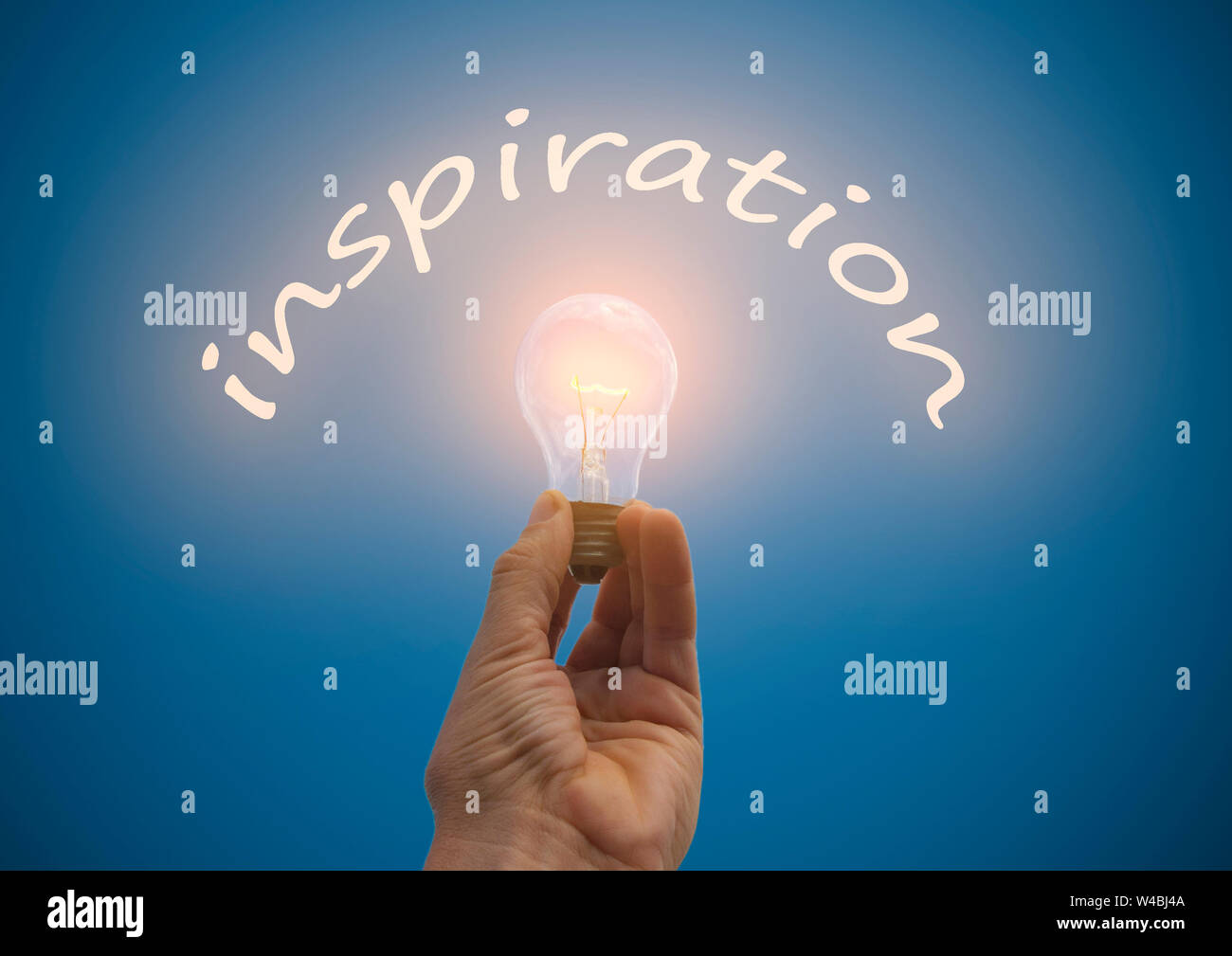 concept burning in hand light bulb with the word inspiration on a blue ...