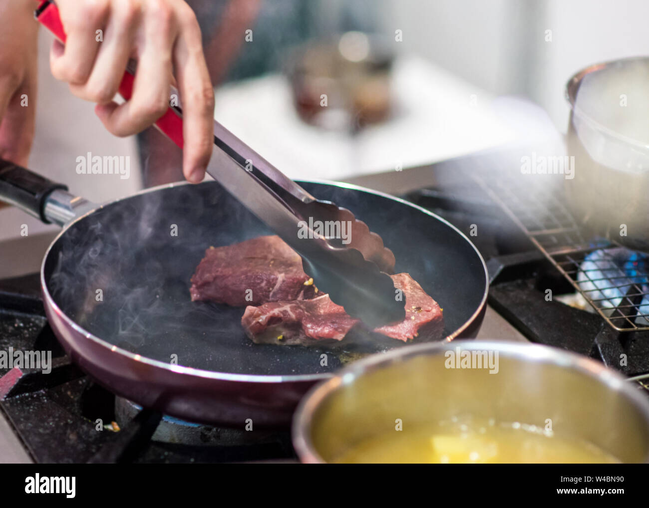Fry the meat in a frying pan. Chef preparing and spicing meat ...