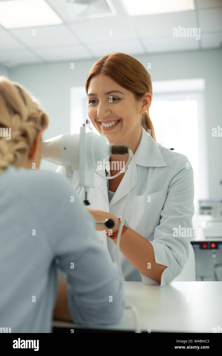 Eye doctor laughing. Red-haired beautiful eye doctor laughing while ...