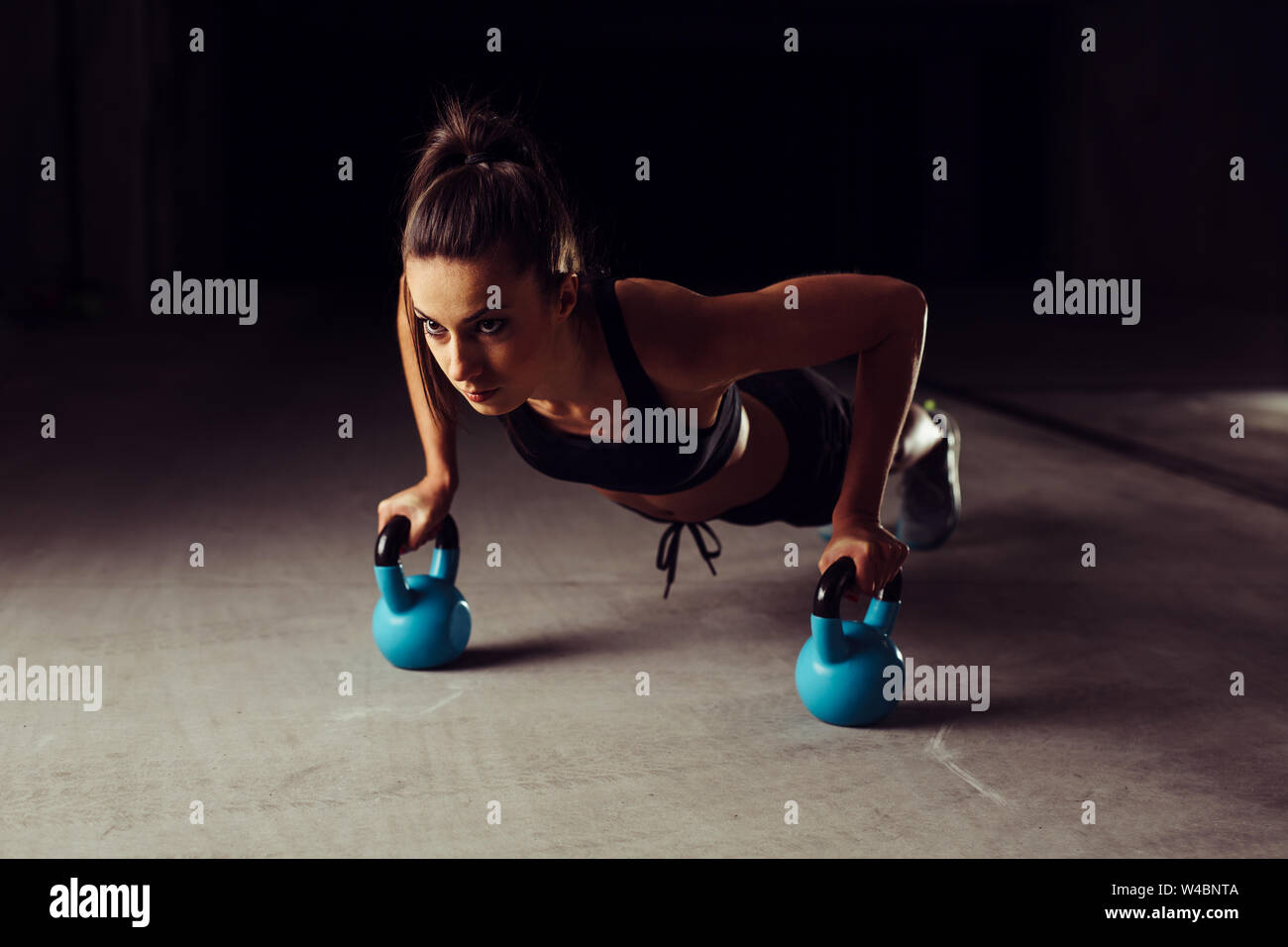 Athlete woman doing push ups on two kettlebells Stock Photo - Alamy