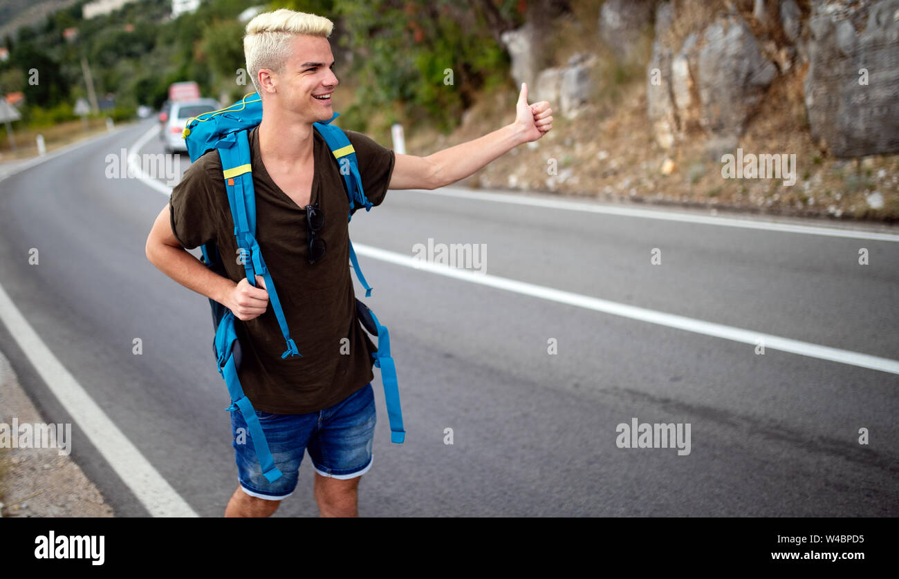 Travel man backpacking hitchhiking on road trip hitching a ride from ...
