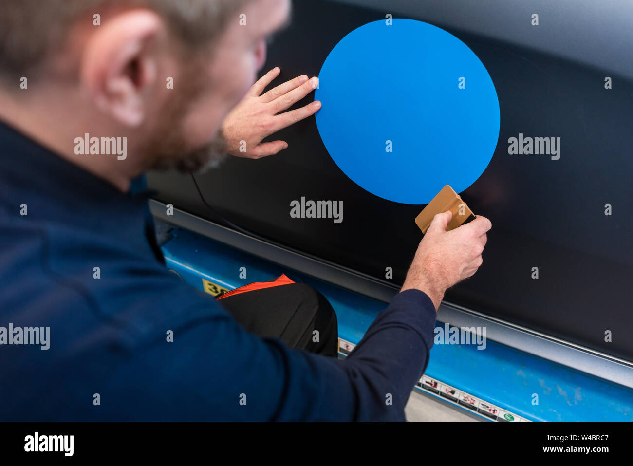 Man putting sticker with company slogan on a car Stock Photo - Alamy