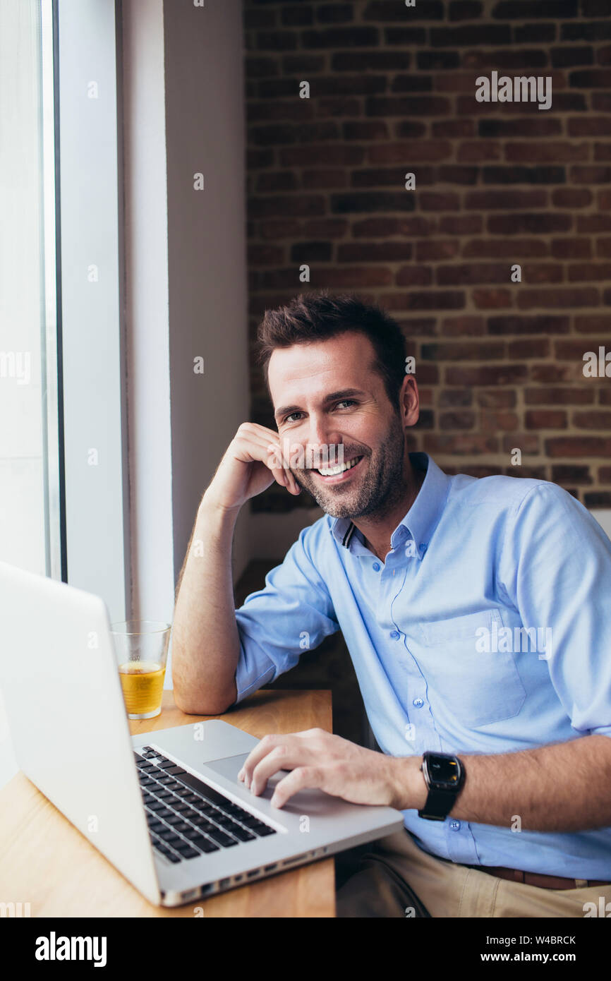 Happy man sitting with computer at office Stock Photo - Alamy