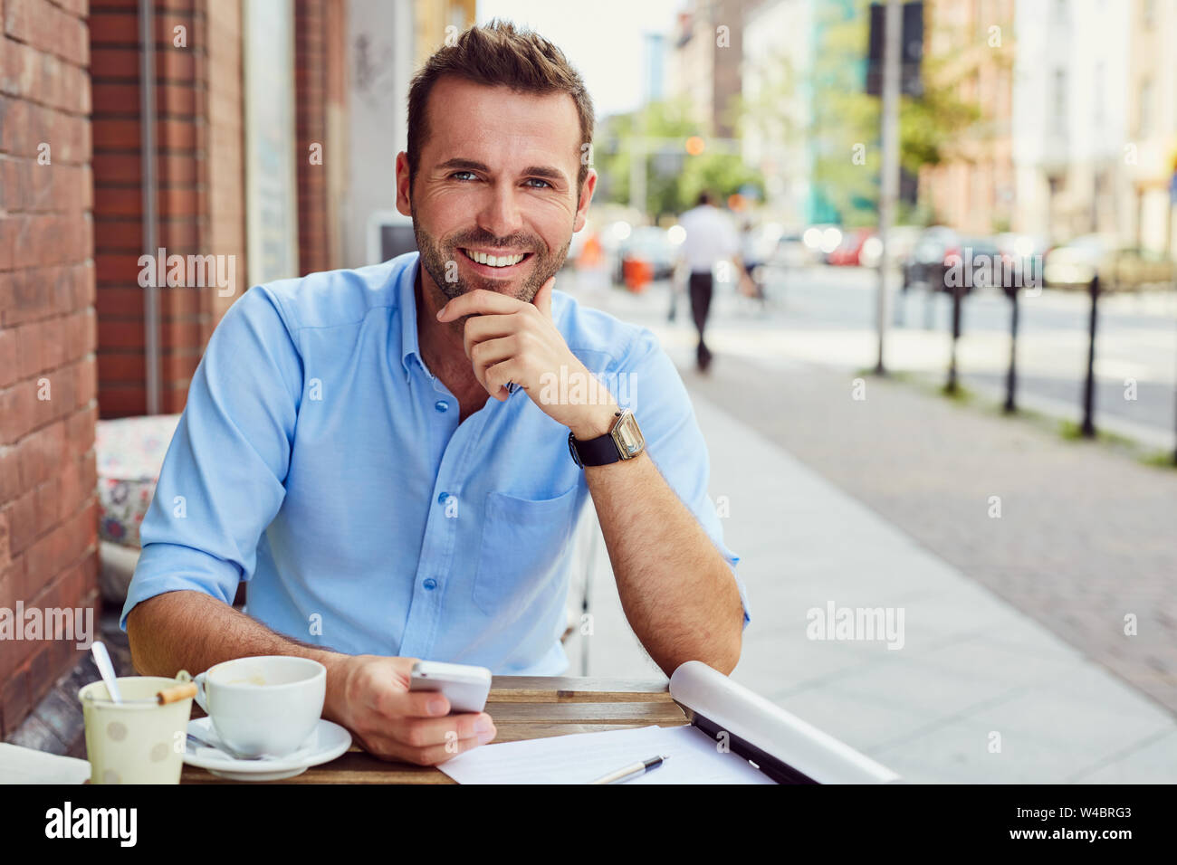 Summer in the city, young man having coffee break at outdoors cafe ...