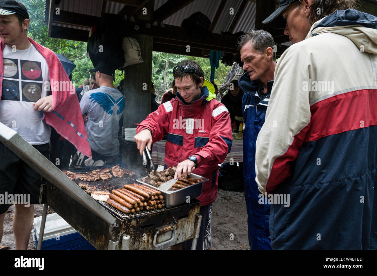 Boat crew members cooking a barbeque of sausages, steaks and beef ...