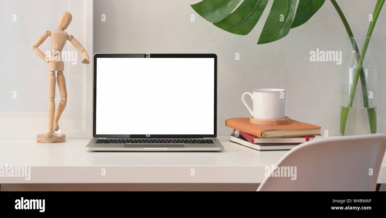 Open blank screen laptop with wooden figure on white table in ...
