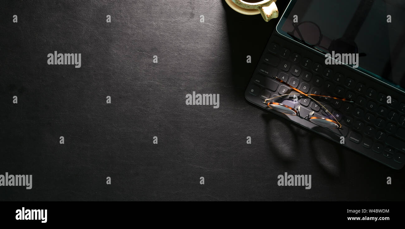 Top view of workspace with laptop computer and other elements on black ...