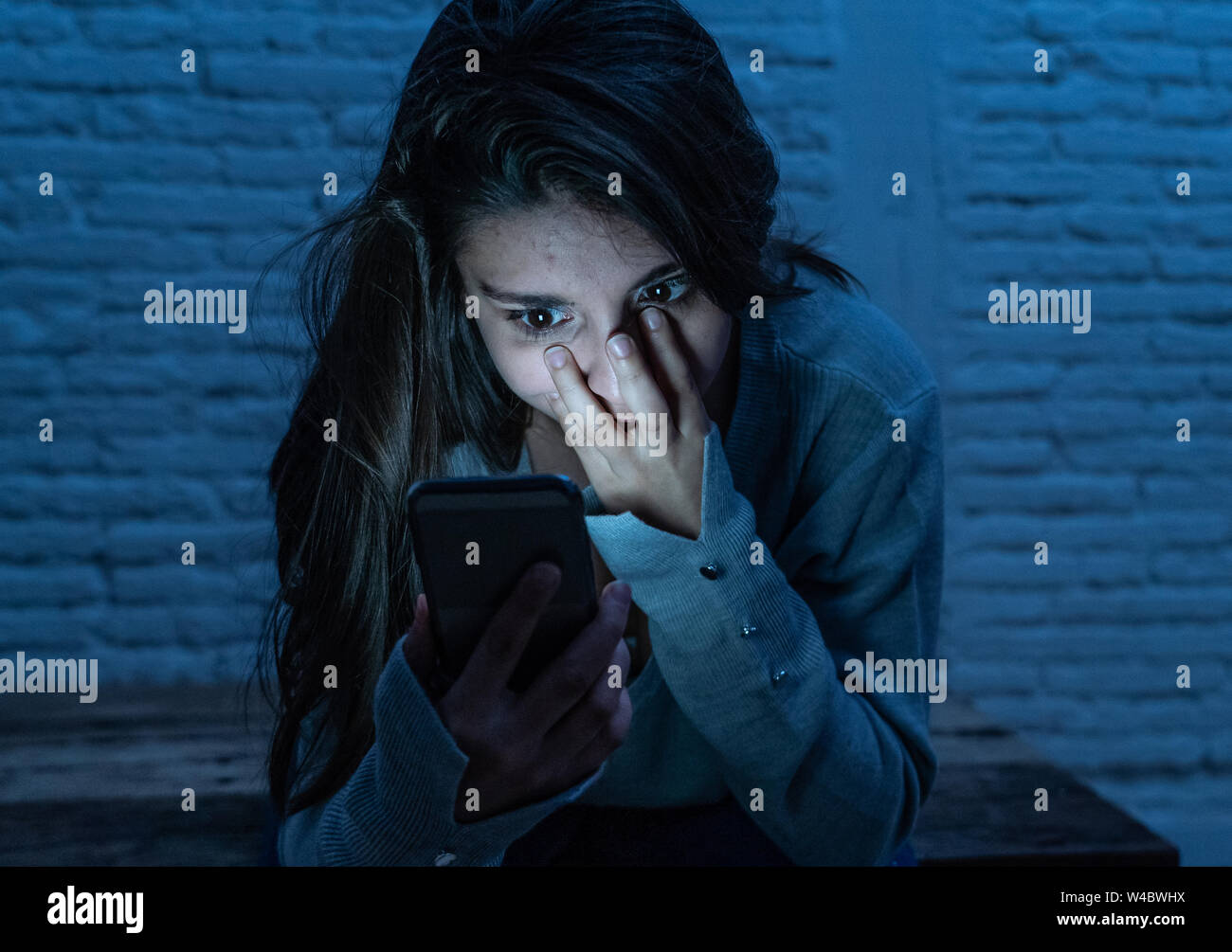 Dramatic portrait of sad scared young woman on smart mobile phone ...