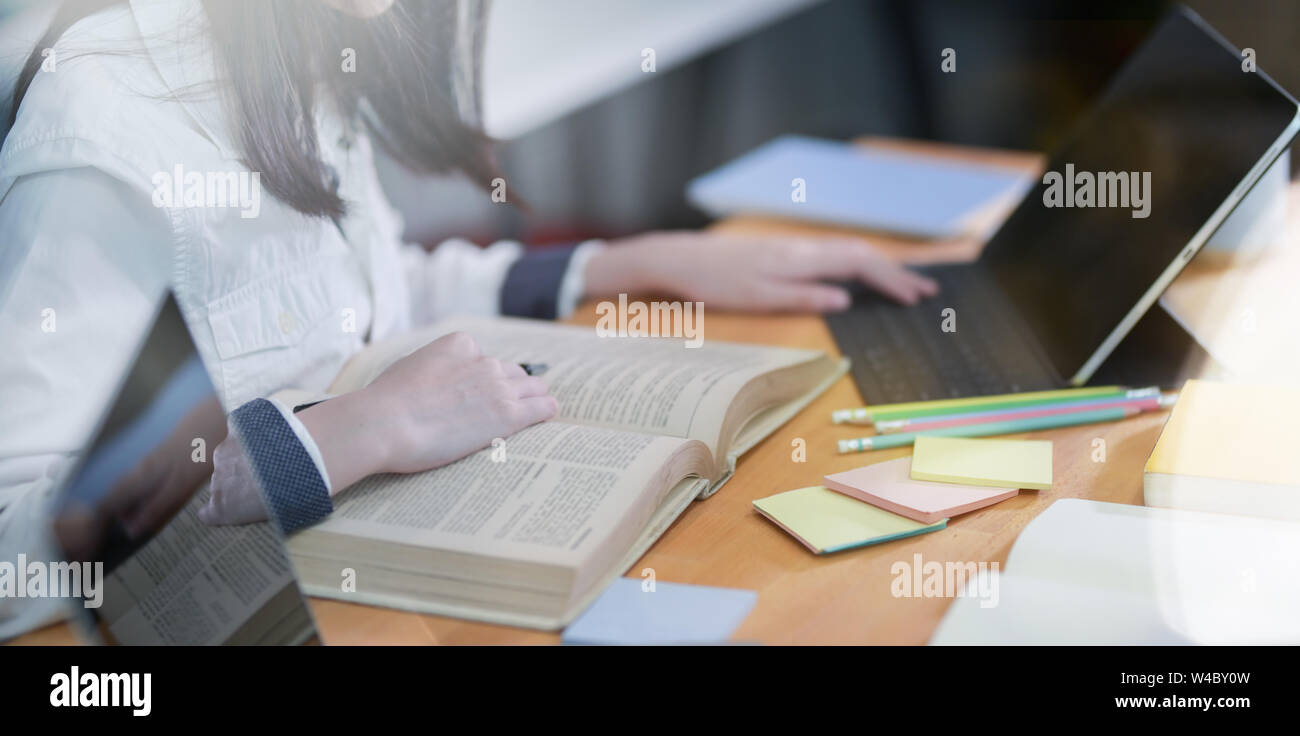 Close-up of female college student working on academic research in ...