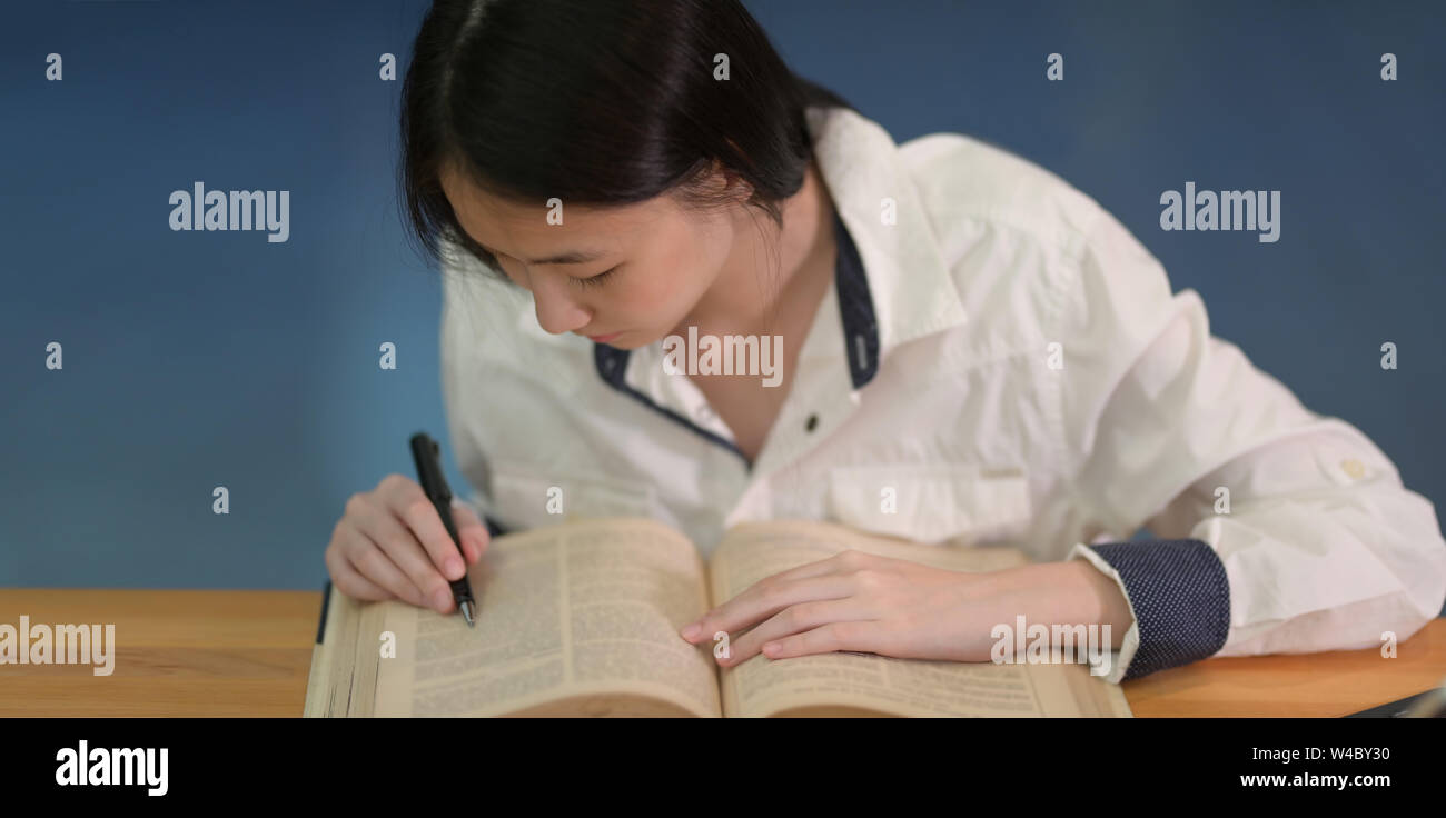 Adorable young collage student studying her exam in school library with ...