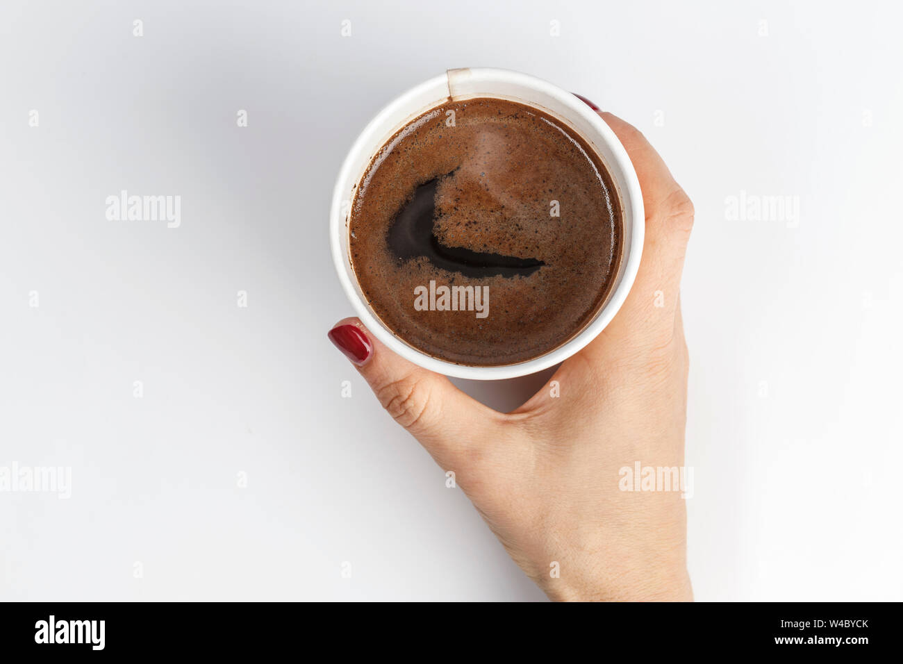 Take-out coffee in hand in a paper cup on a white background. space for ...