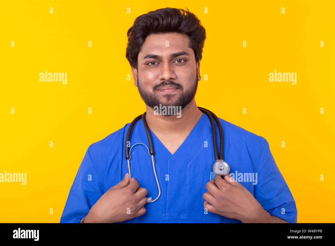 Male Indian doctor with a stethoscope posing on a yellow background ...