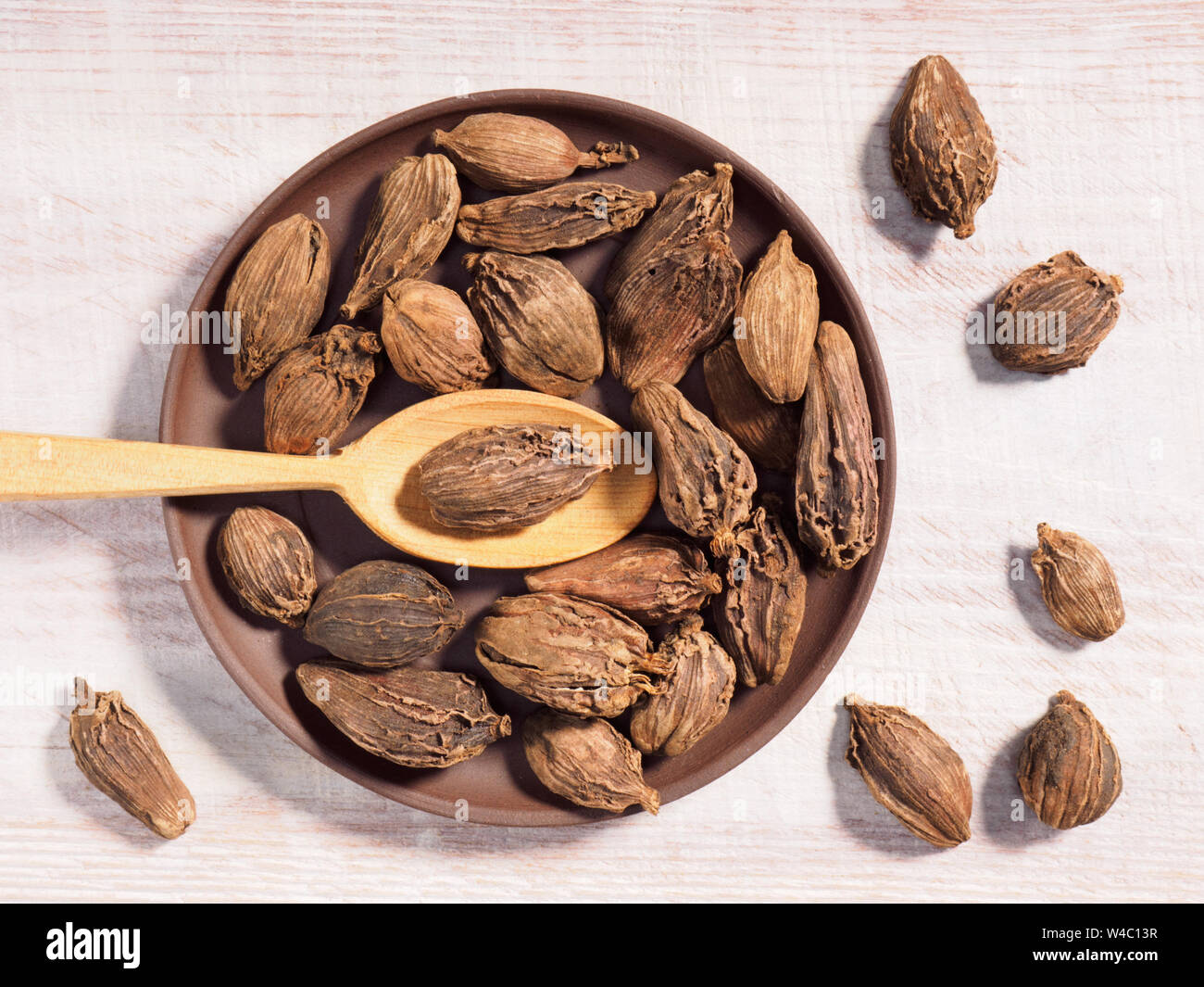 Black cardamom (Amomum subulatum) on a brown clay plate on a wooden ...