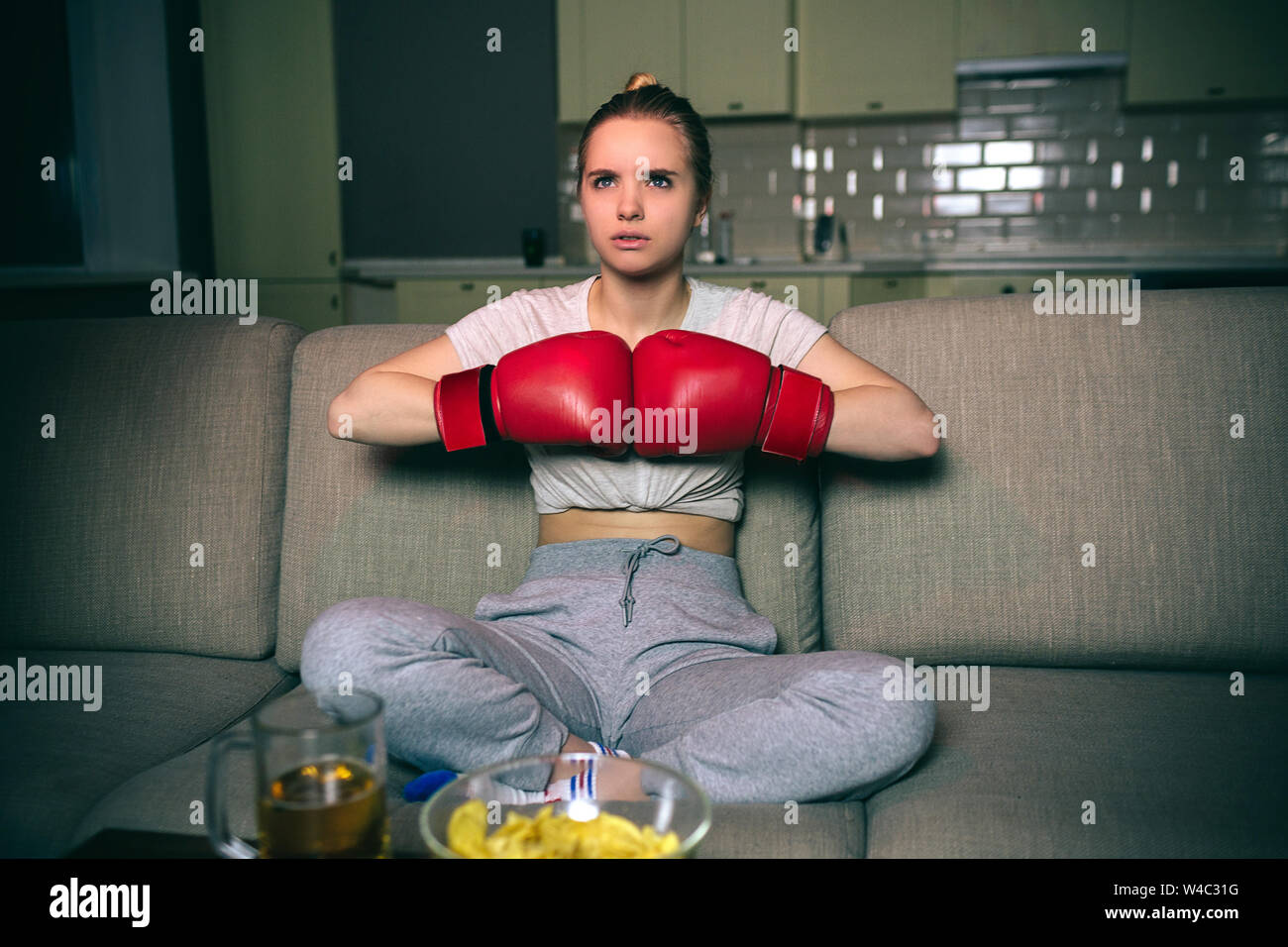 Young woman watch boxing on tv at night. Sitting with legs crossed and ...