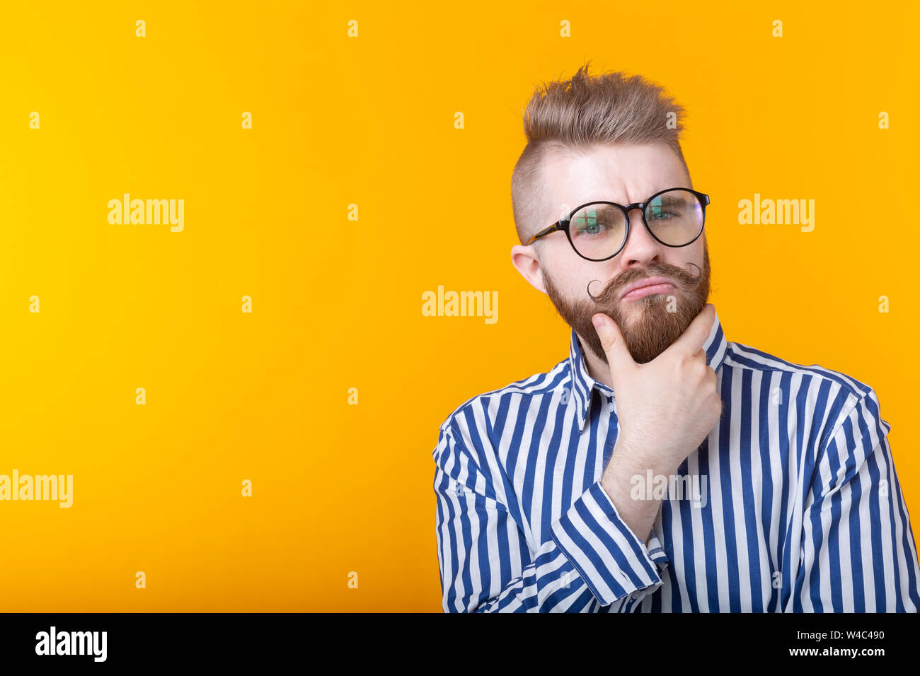 Cute intelligent young man with a beard and with glasses poses on a ...