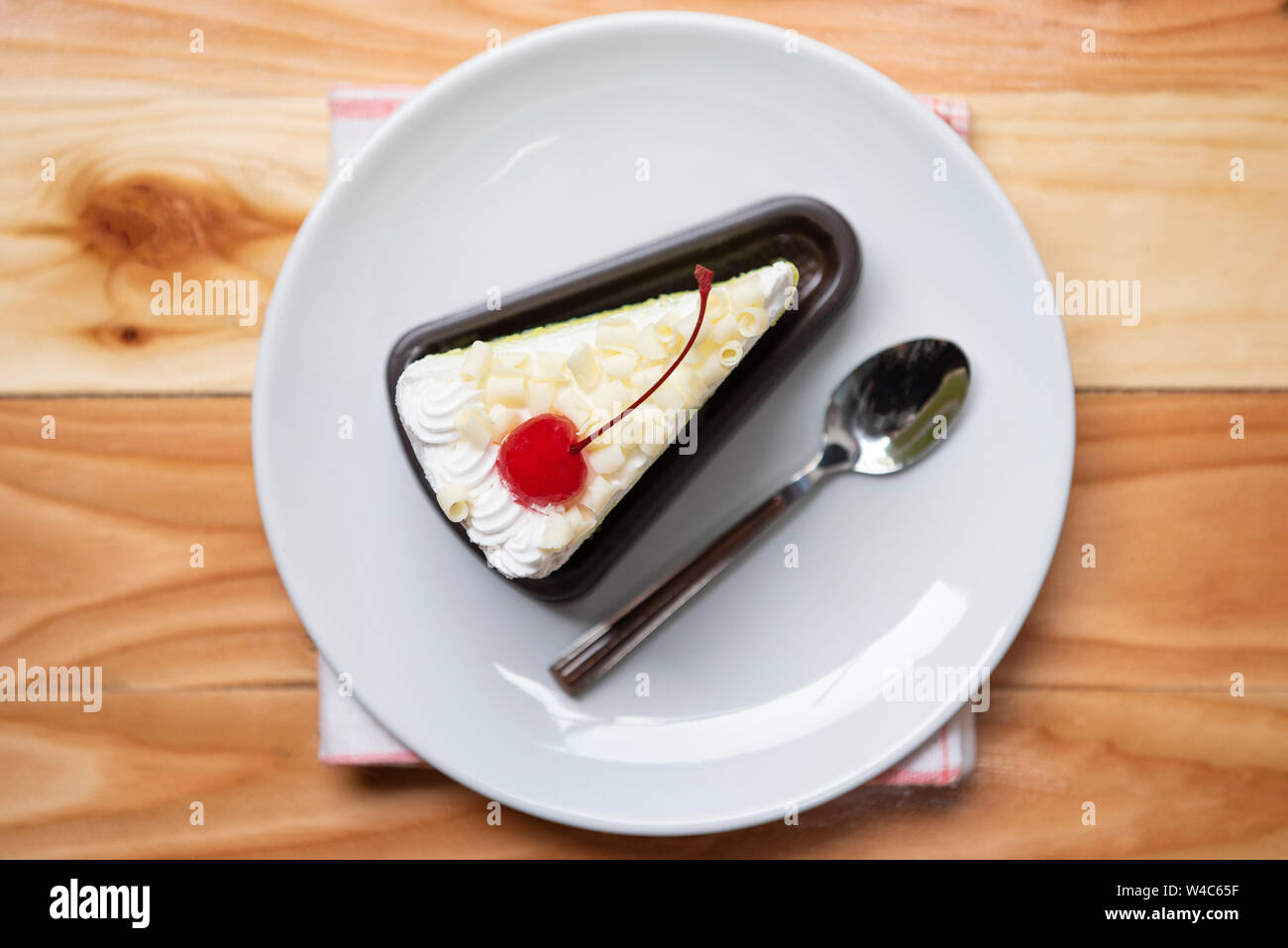 Cake slice top view with cherry fruit and cream on white palte on the ...