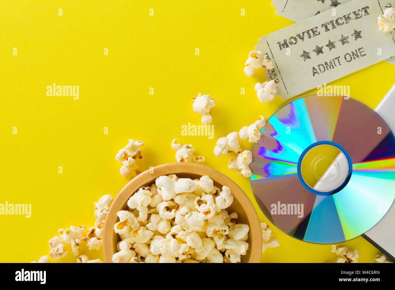 Movie tickets, DVD or blu ray disc and popcorn on yellow table ...