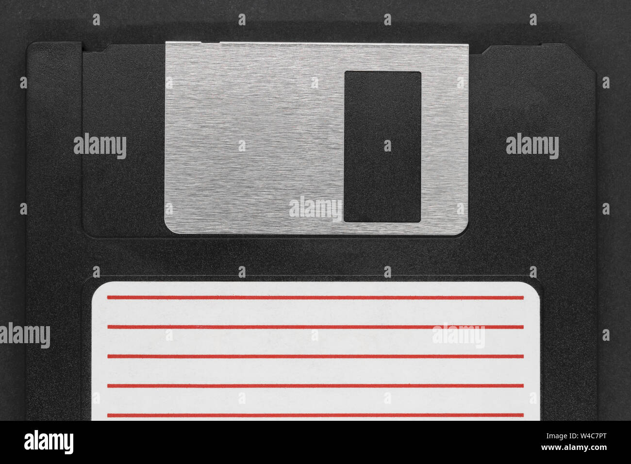 Part of black floppy disk with white information sticker with red lines ...
