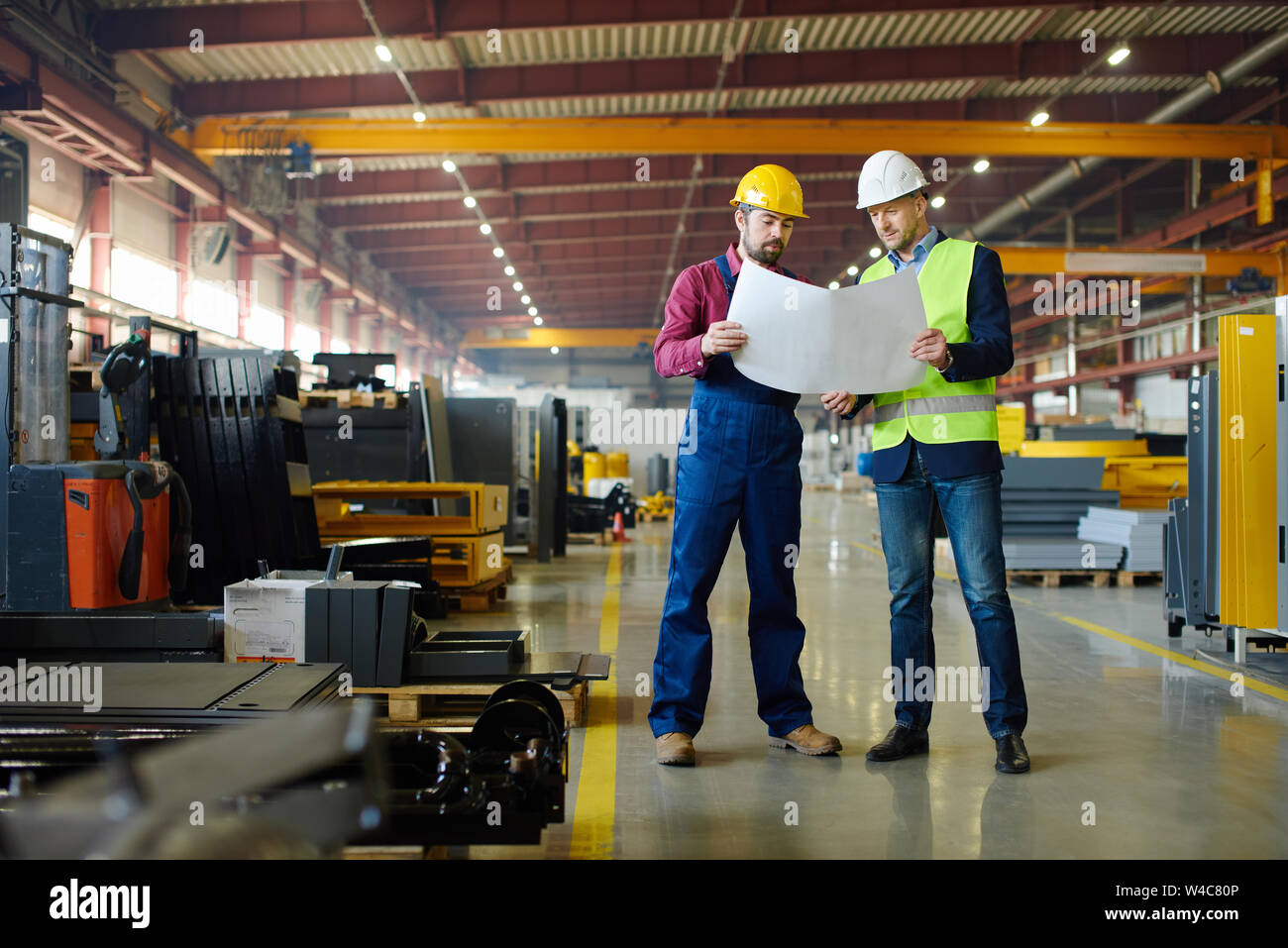 Engineers in hard hats working on a blueprint at the industrial plant ...