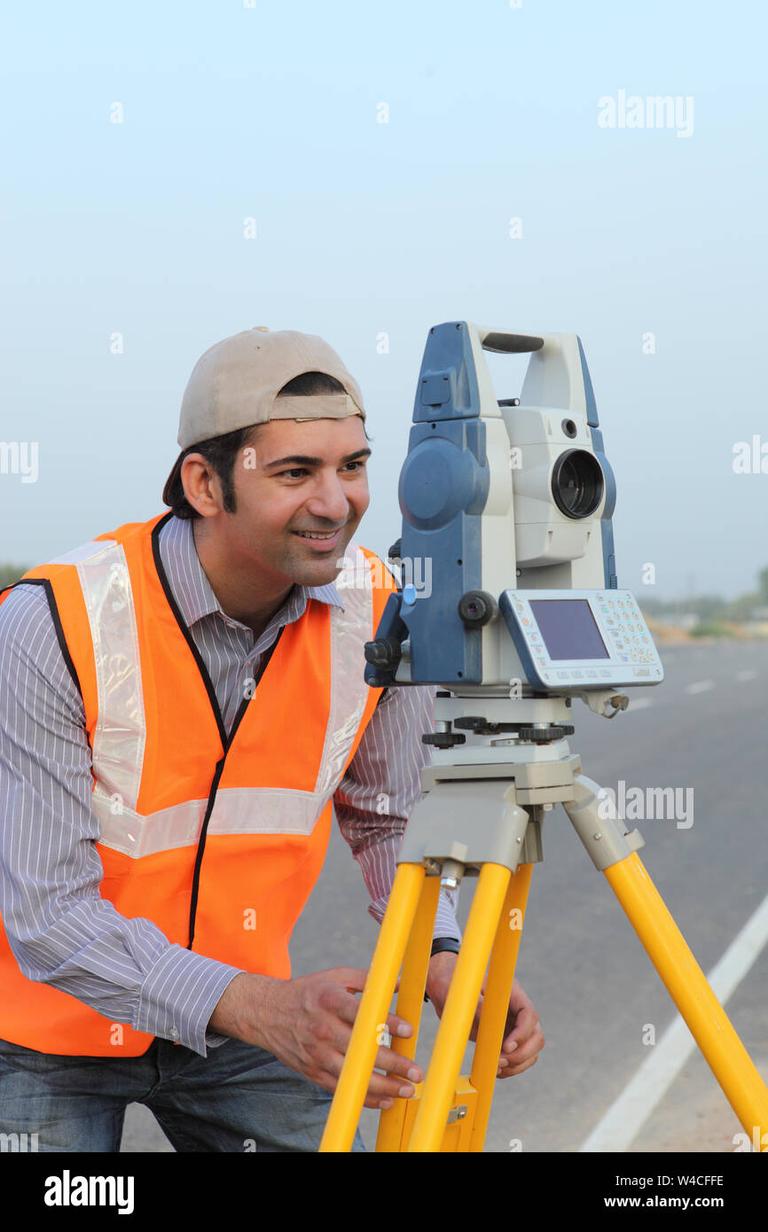 Surveyor using theodolite on tripod Stock Photo - Alamy